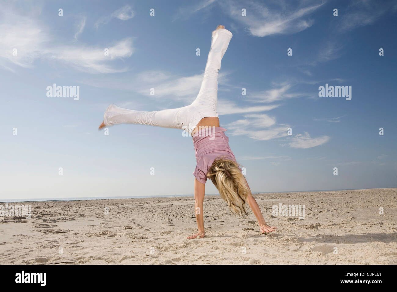 Germany, Schleswig Holstein, Amrum, Woman cartwheeling on beach Stock ...