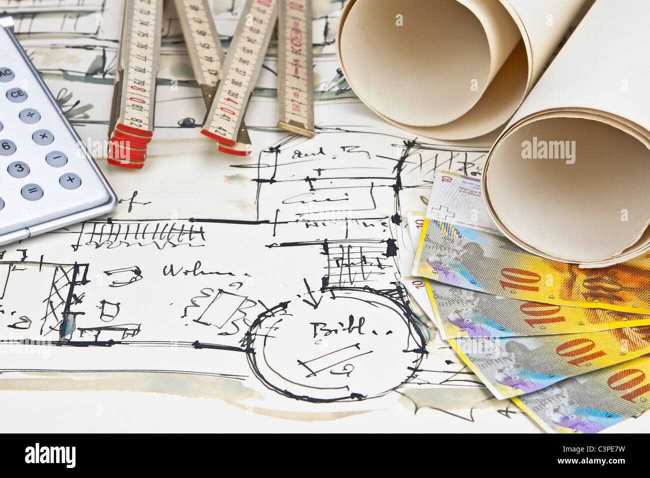 the blueprint of a house with two paper rolls, a calculator, a rule and ...