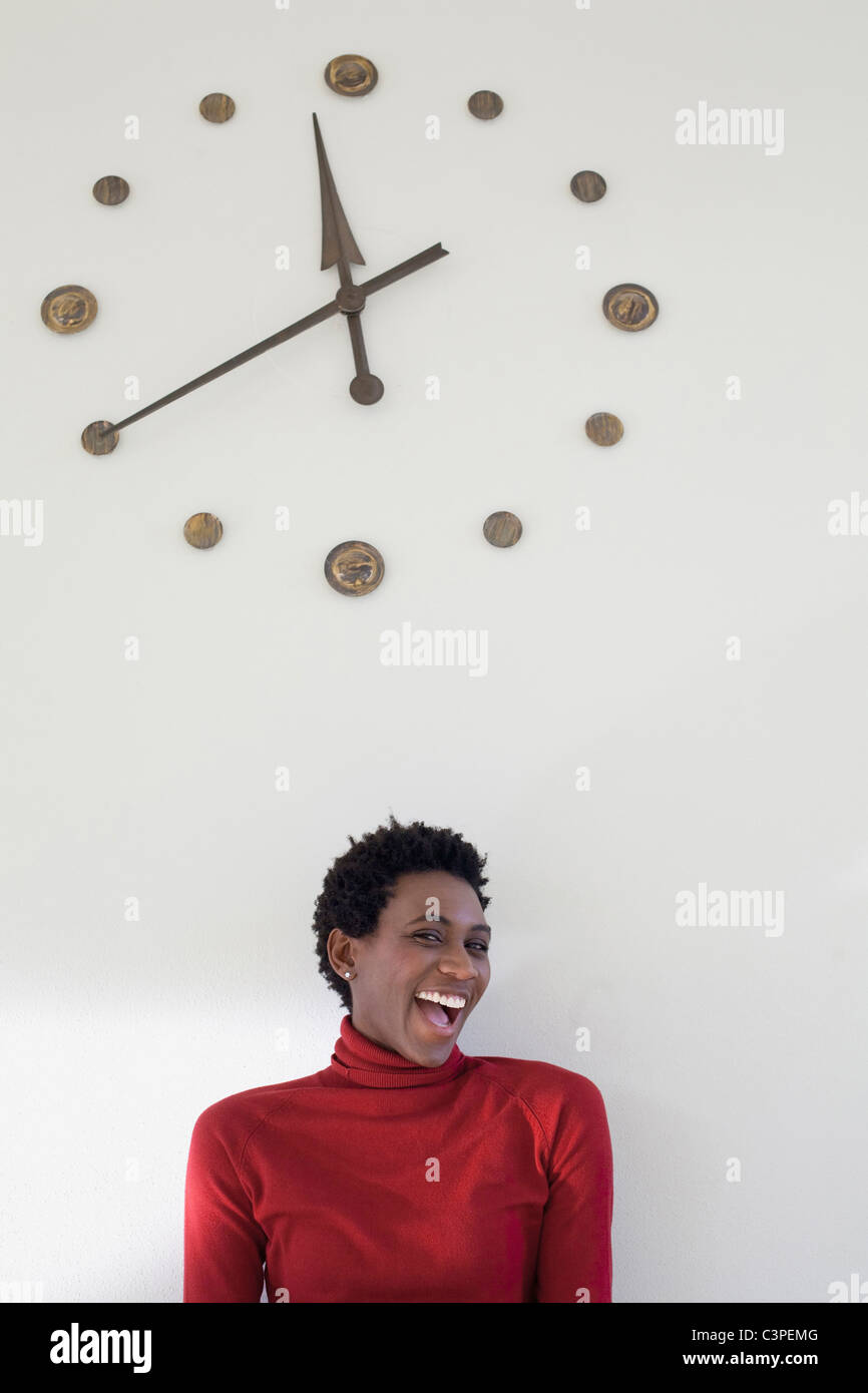 Germany, Leipzig, University student laughing with wall clock in ...