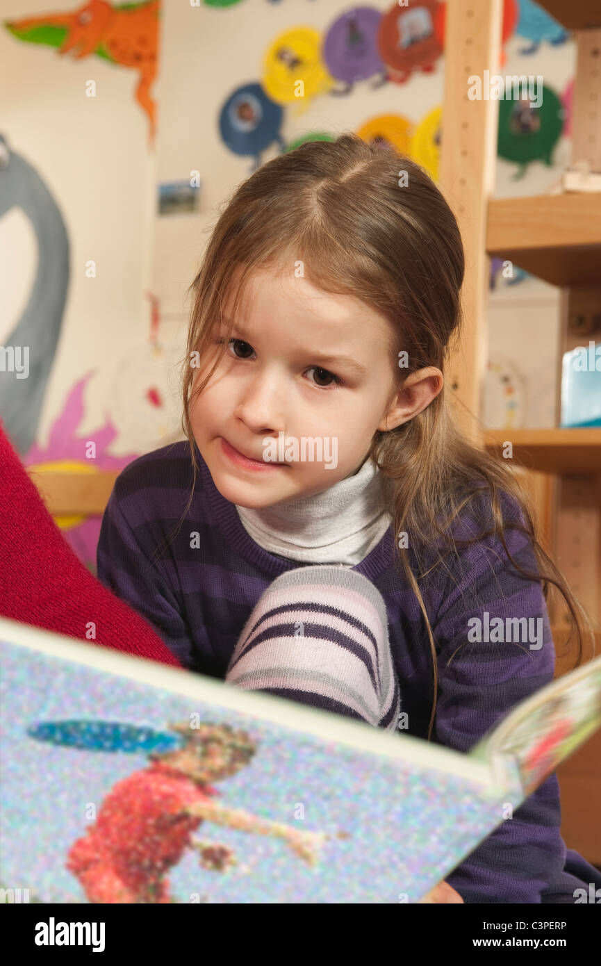 Germany, Girl (4-5) in nursery reading a book, portrait Stock Photo - Alamy
