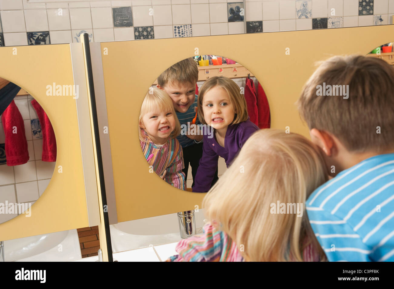 Germany, Three children in lavatory, boy (4-5) holding toothbrush ...