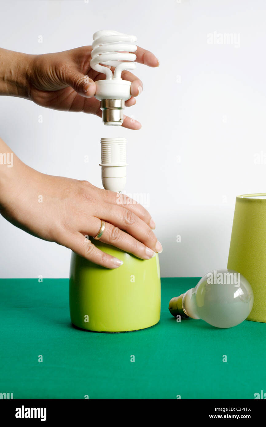 woman changing old style traditional incandescent light bulb in table ...