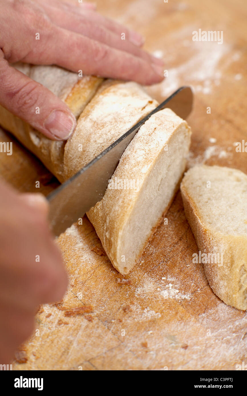 Person cutting baguette, elevated view Stock Photo - Alamy