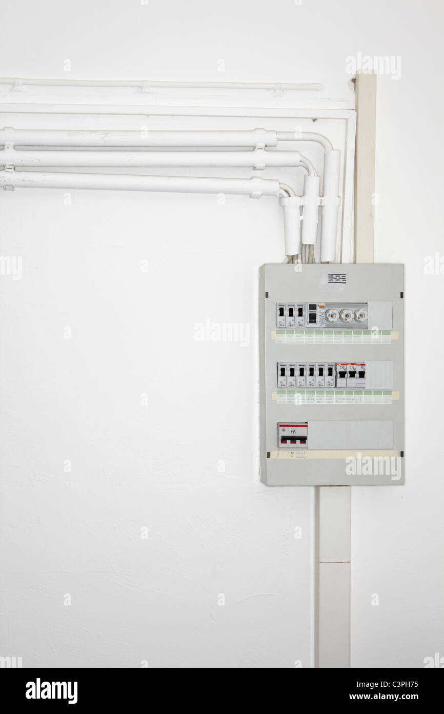 Pipes, electric cables and fuse box on white wall Stock Photo - Alamy