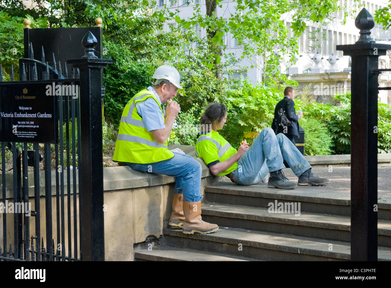 British Worker or workers sitting in safety jackets & hard hat on steps ...