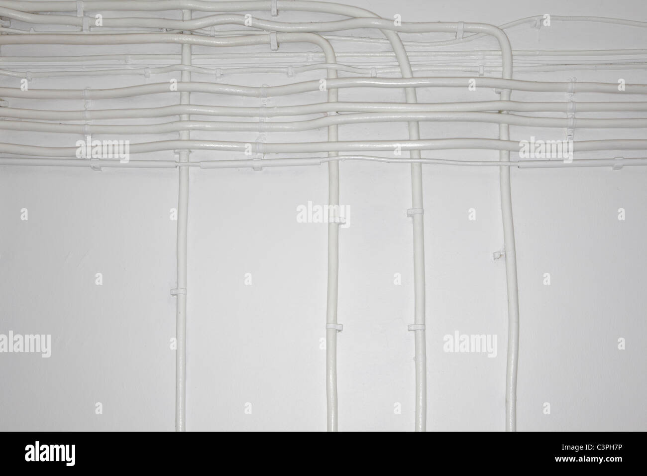 Pipes and electric cables on white wall Stock Photo - Alamy