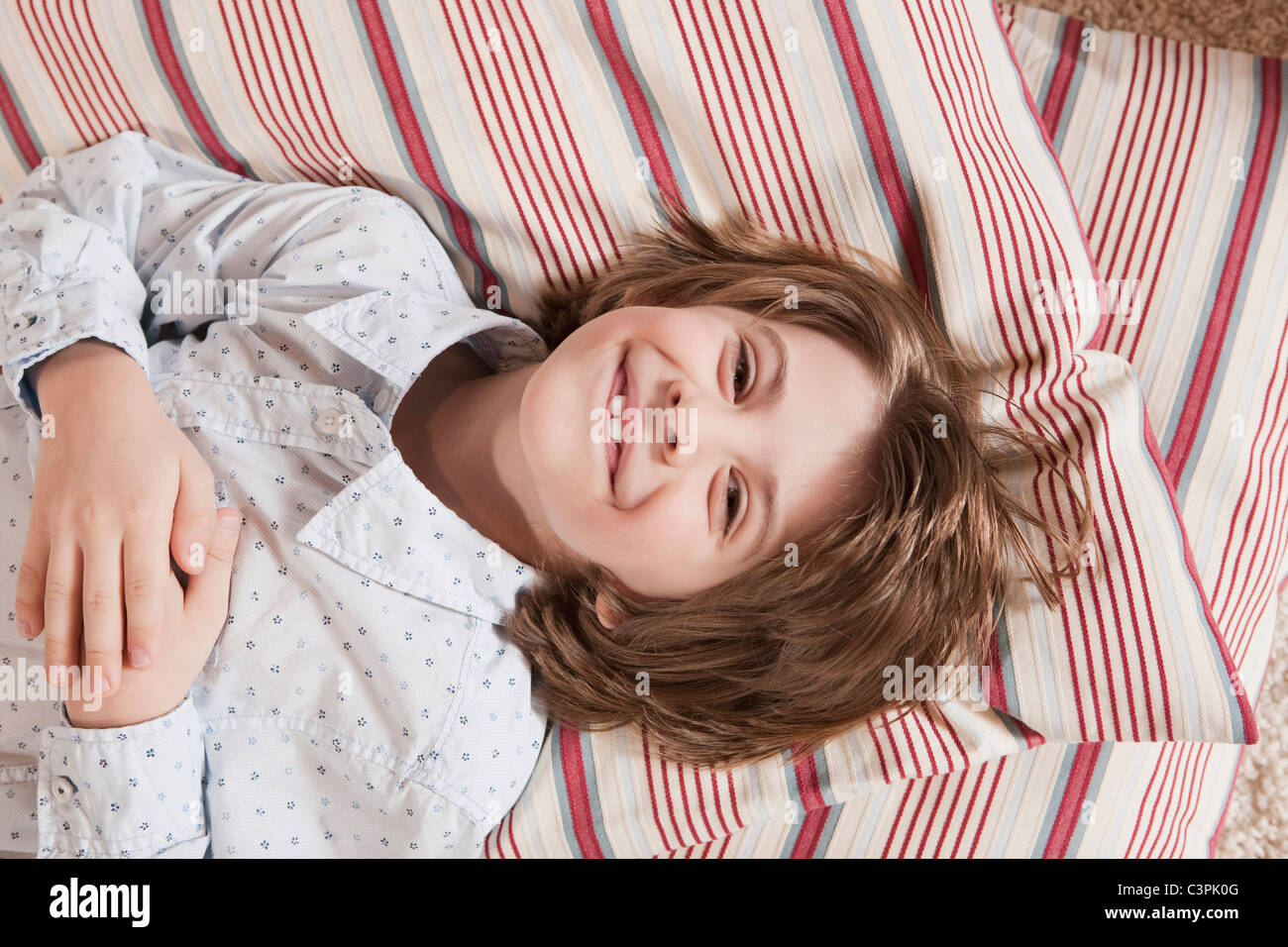 Germany, Cologne, Boy (6-7) lying on cushion, elevated view Stock Photo ...