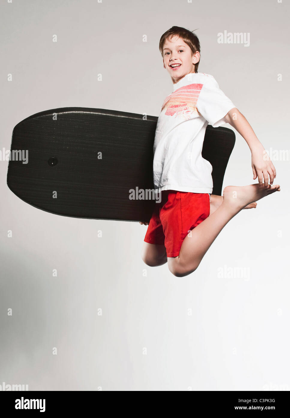 Boy (12-13) jumping with boogie board, smiling, portrait Stock Photo ...