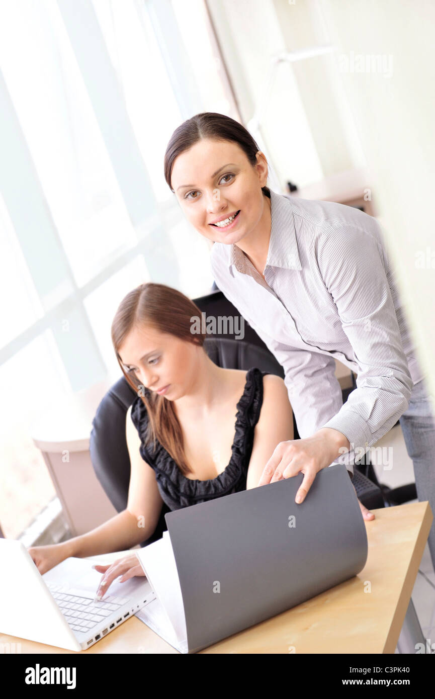 Portrait of two pretty women in an office environment working together ...