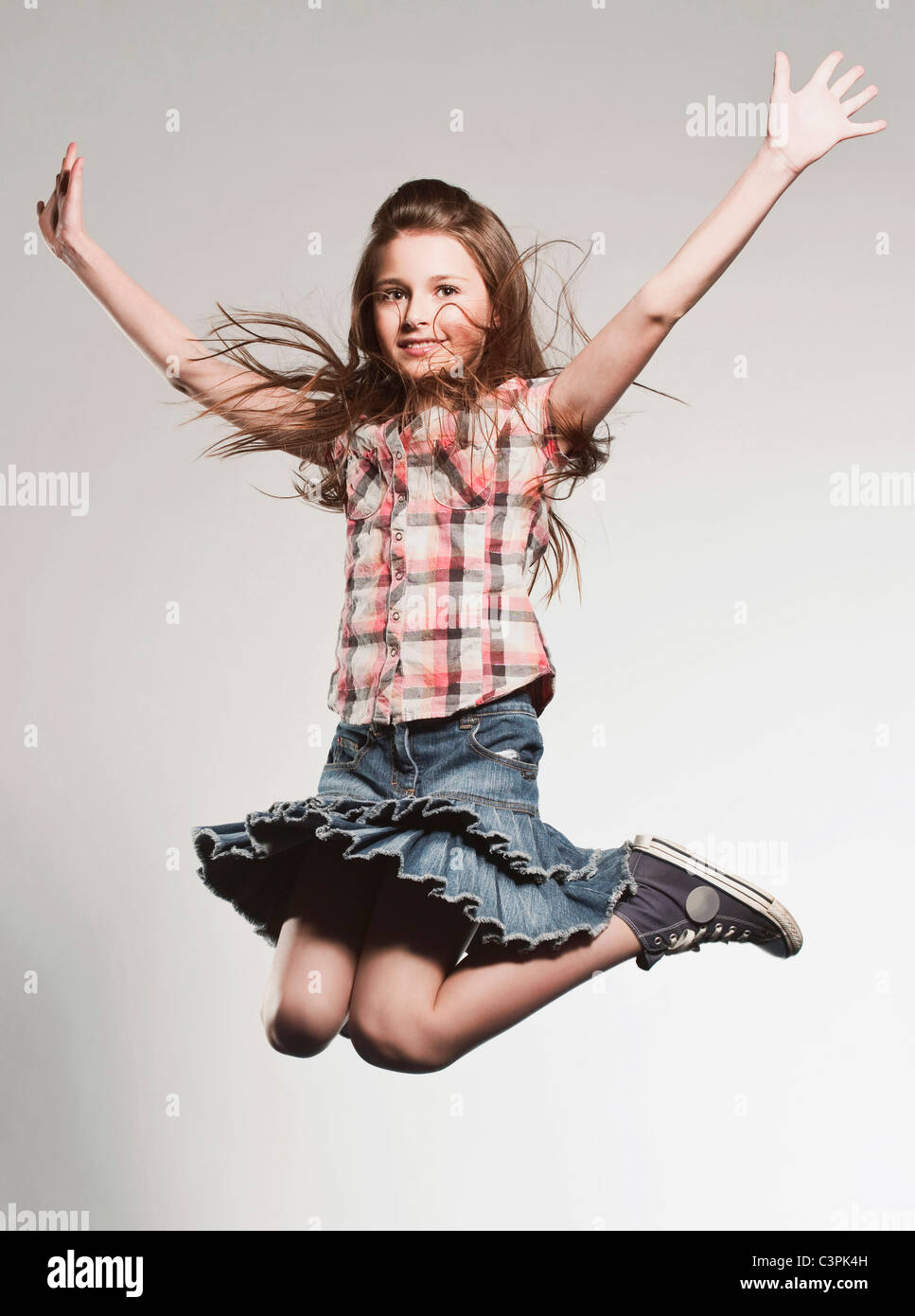 Girl (8-9) jumping with arms up, smiling Stock Photo - Alamy