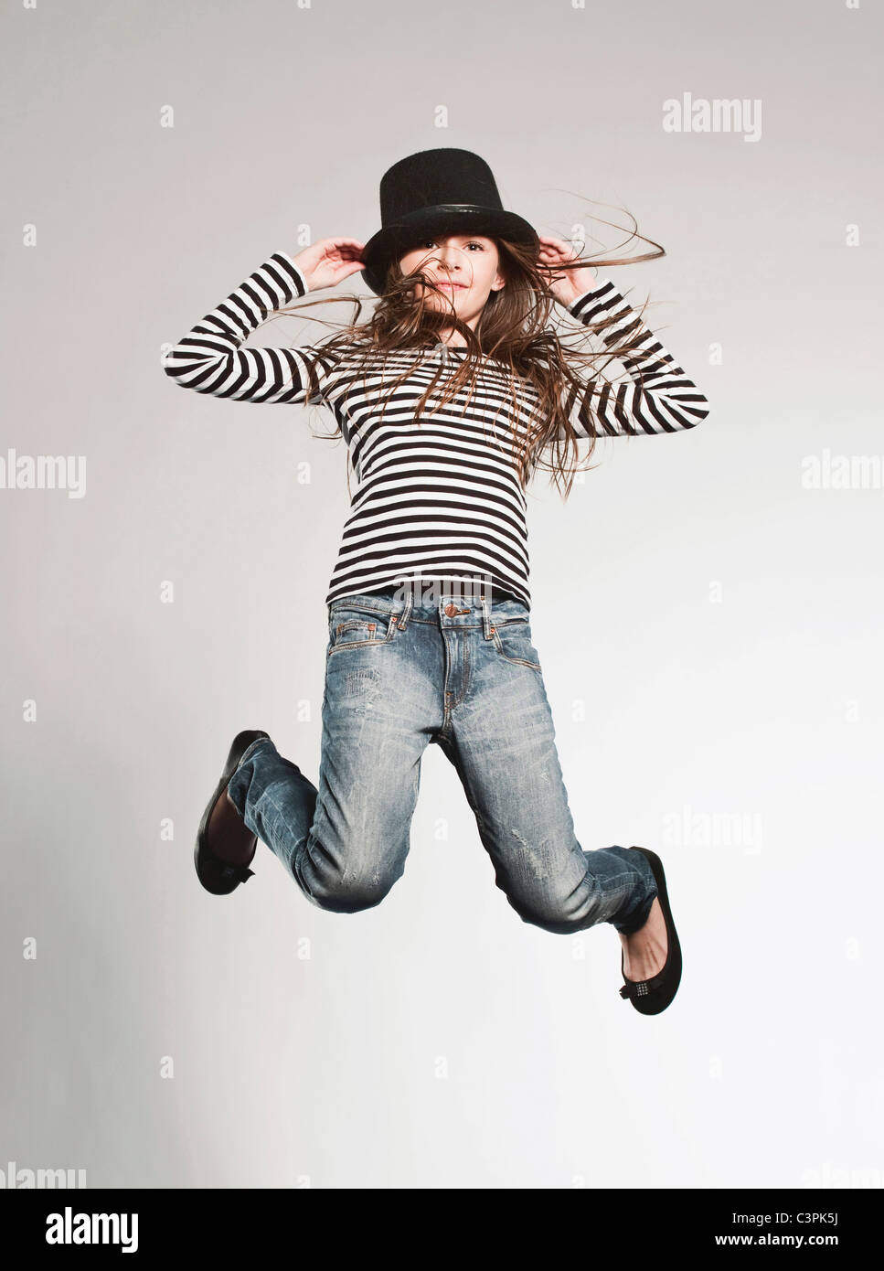 Girl (8-9) wearing hat and jumping, smiling, portrait Stock Photo - Alamy