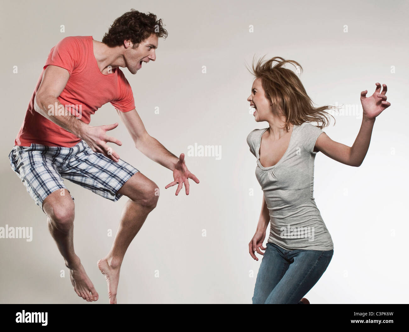 Man and woman shouting and jumping against gray background Stock Photo ...