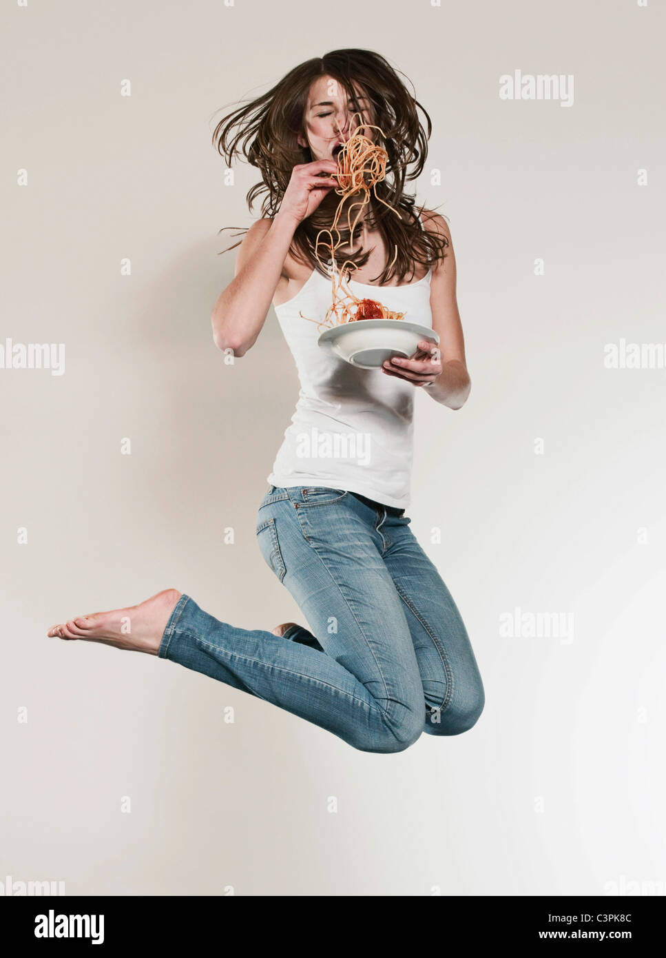 Teenage girl (16-17) jumping and eating noodles Stock Photo - Alamy