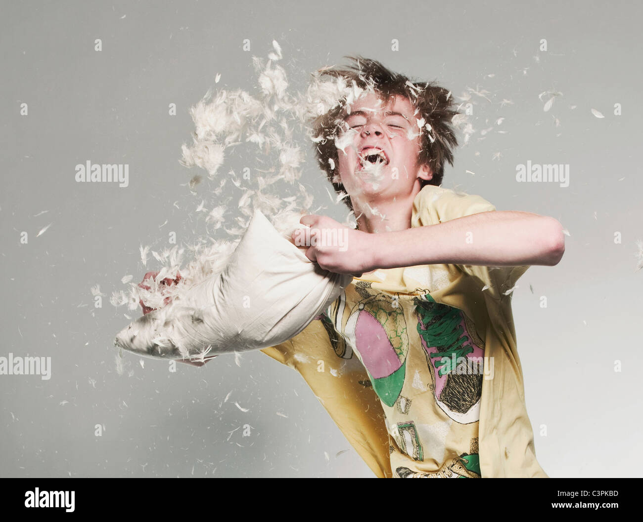 Teenage boy (16-17) tearing pillow Stock Photo - Alamy