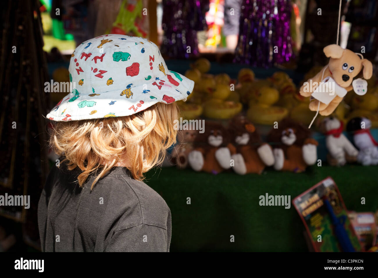 A young child looking longingly at a prize in a stall at the fair ...