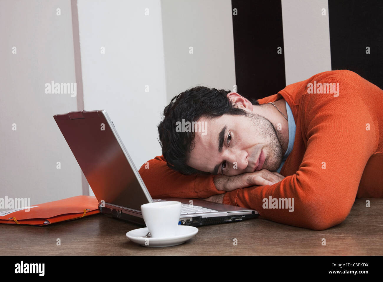 Tired man with coffee cup and laptop Stock Photo - Alamy