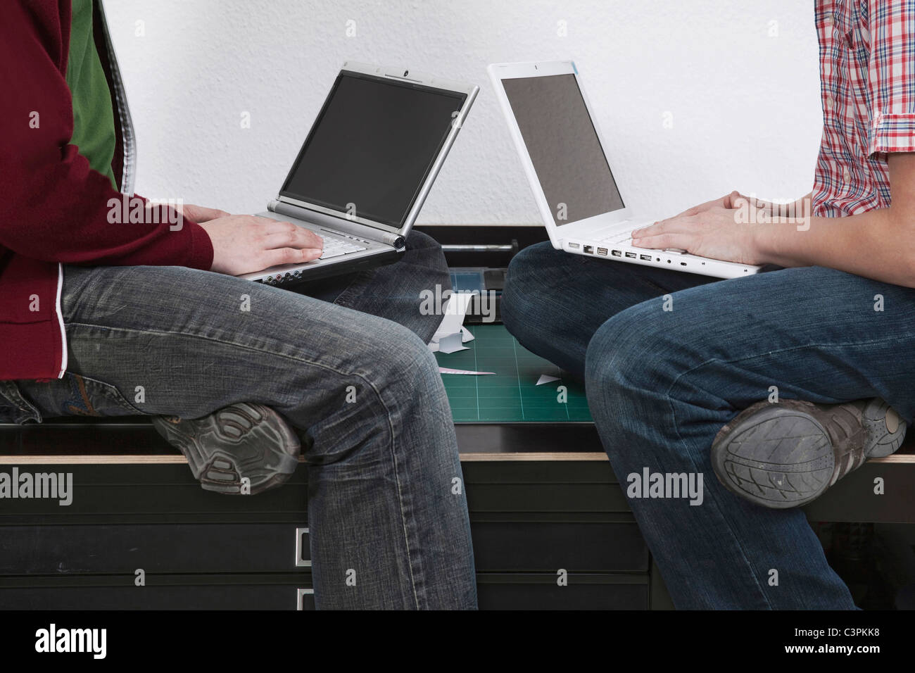 Men sitting on desk using laptop Stock Photo - Alamy