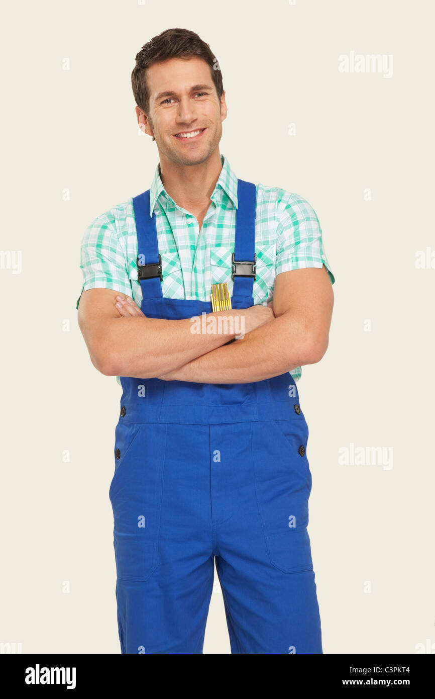 Man wearing overall smiling, arms crossed, portrait Stock Photo - Alamy