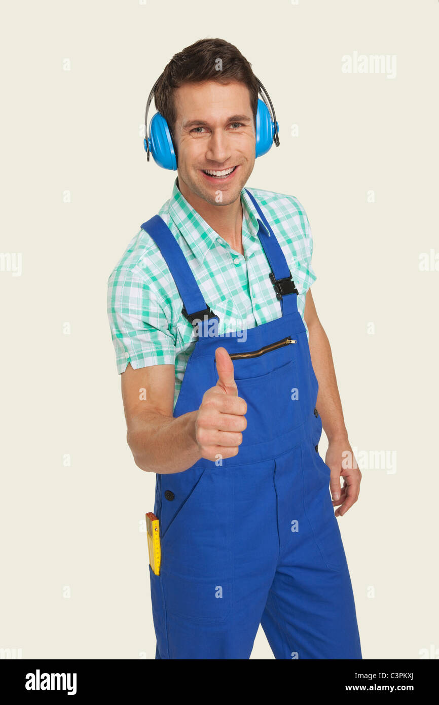 Man wearing ear muff showing thumbs up sign, smiling, portrait Stock ...