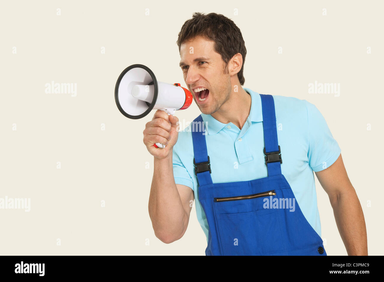 Man in overall shouting through megaphone Stock Photo - Alamy