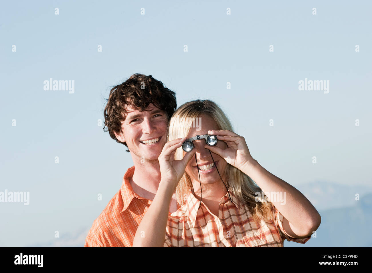 Young couple standing, woman uses binoculars Stock Photo - Alamy