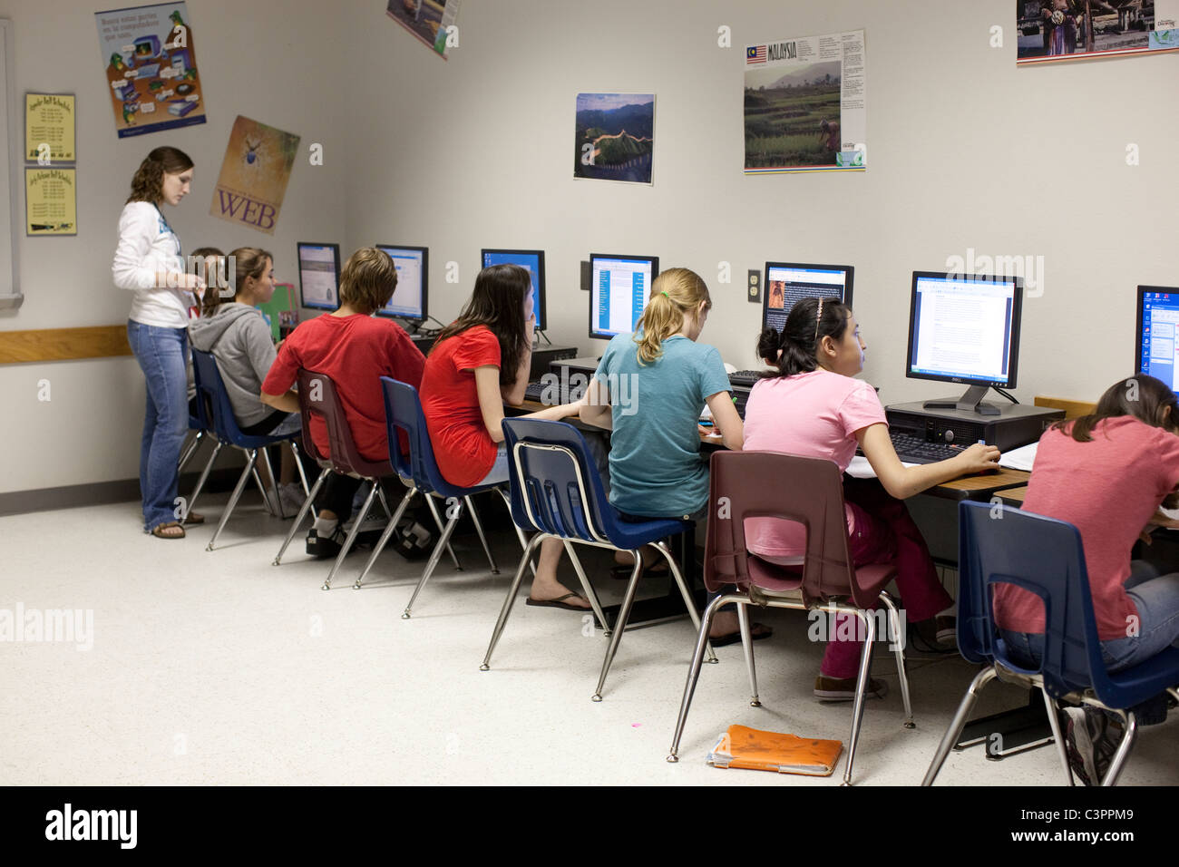 Anglo female teacher answers student's question in computer lab at ...