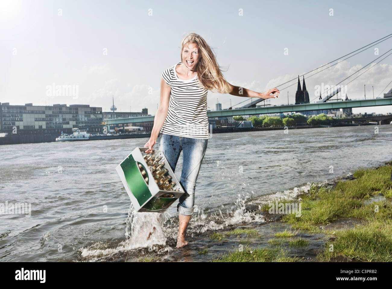 Germany, Cologne, Woman carrying case of beer at rhein river Stock ...