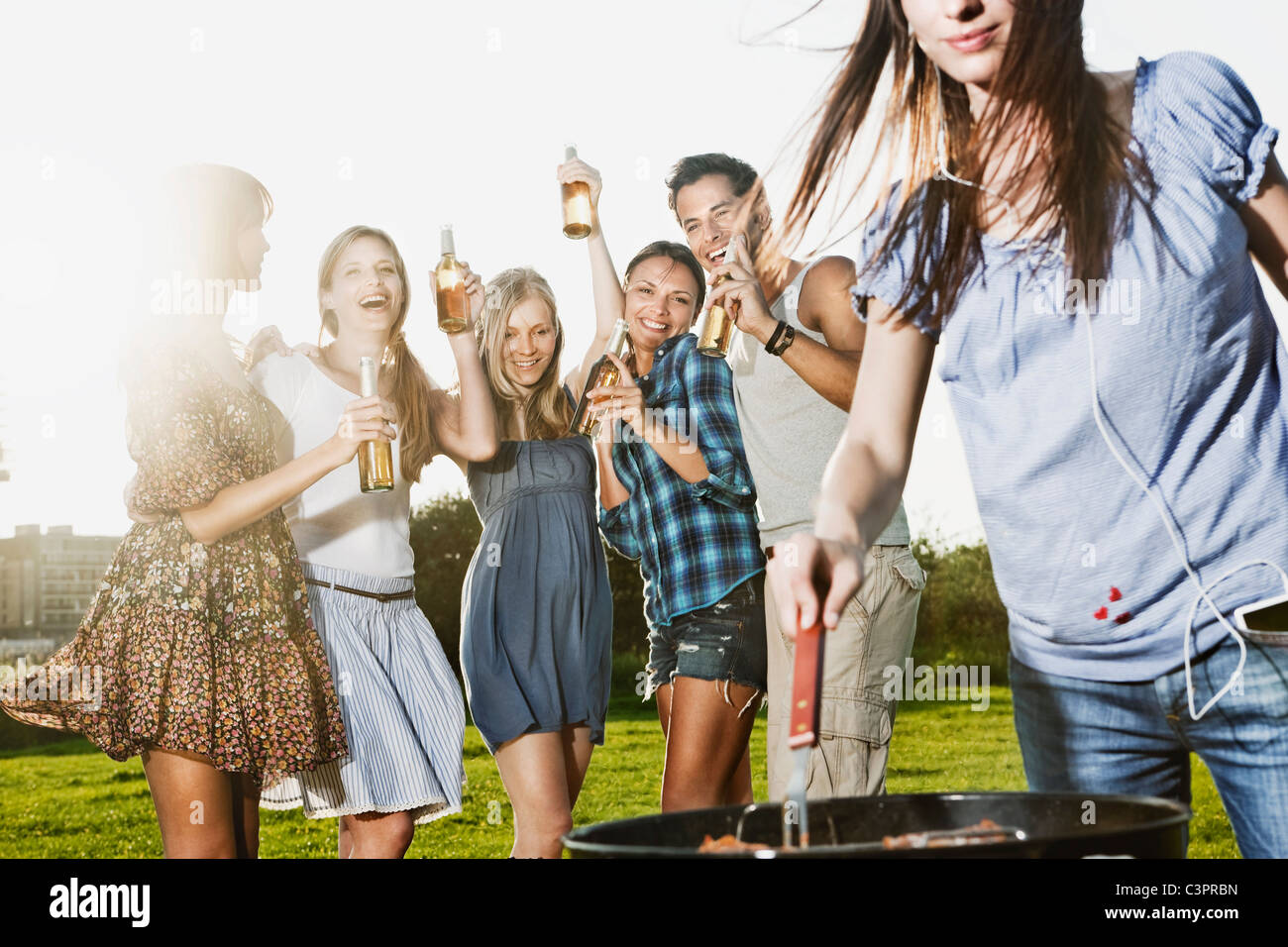 Germany, Cologne, Woman barbecueing with friends in background Stock ...