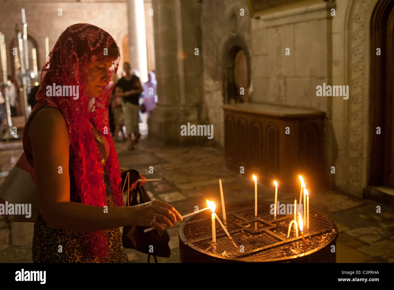 A shrouded woman lights a candle in a temple in Jerusalem Stock Photo ...