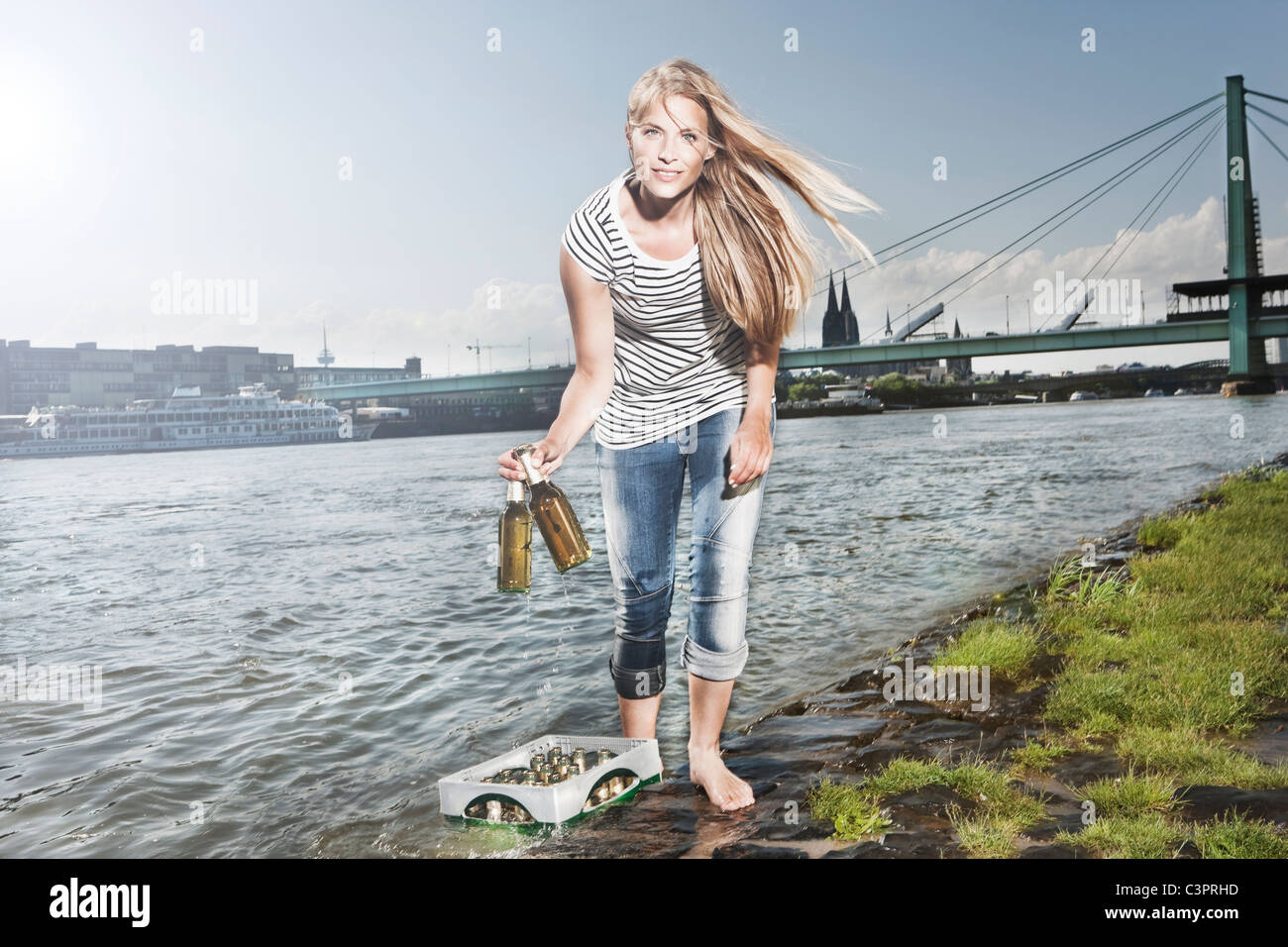 Germany, Cologne, Woman with case of beer at rhein river Stock Photo ...