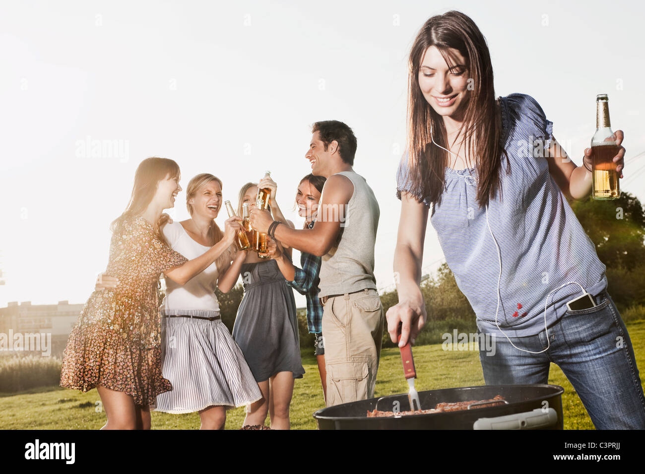 Germany, Cologne, Woman barbecueing with friends in background Stock ...