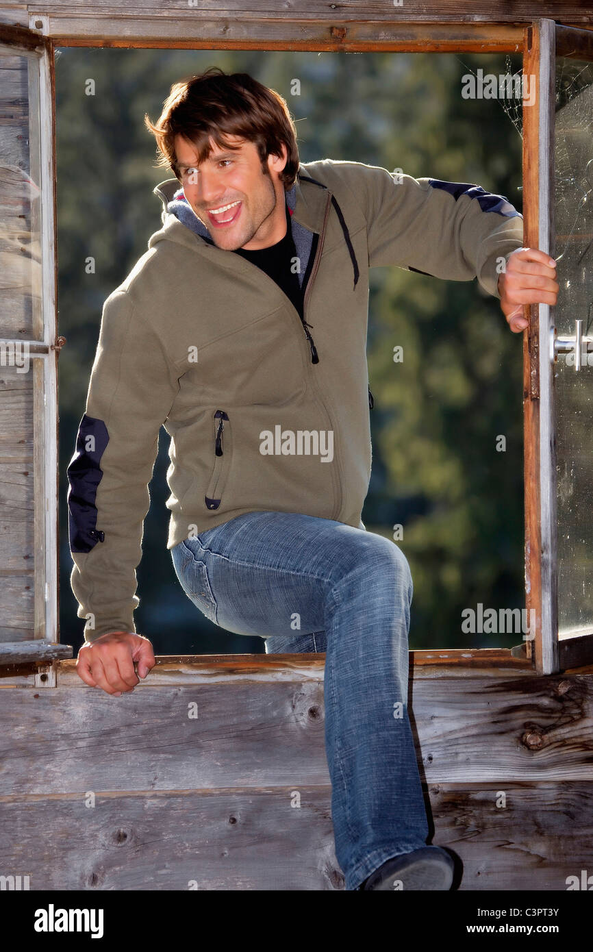 Germany, Bavaria, Man entering through window, smiling Stock Photo - Alamy