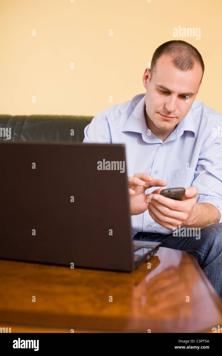 Casually dressed young businessman using mobile phone and laptop Stock ...