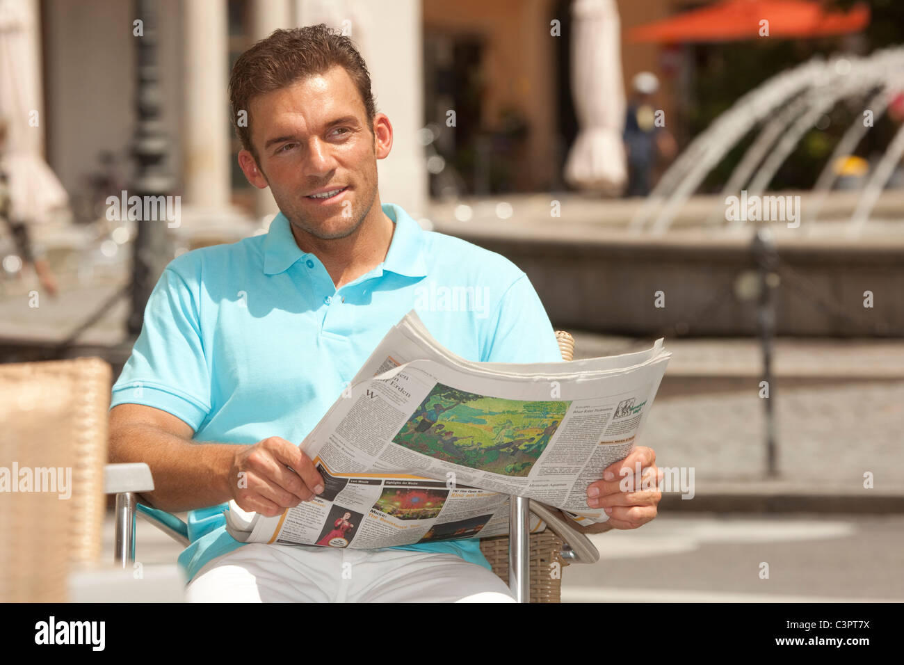 Germany, Bavaria, Regensburg, Man sitting with newspaper, smiling Stock ...
