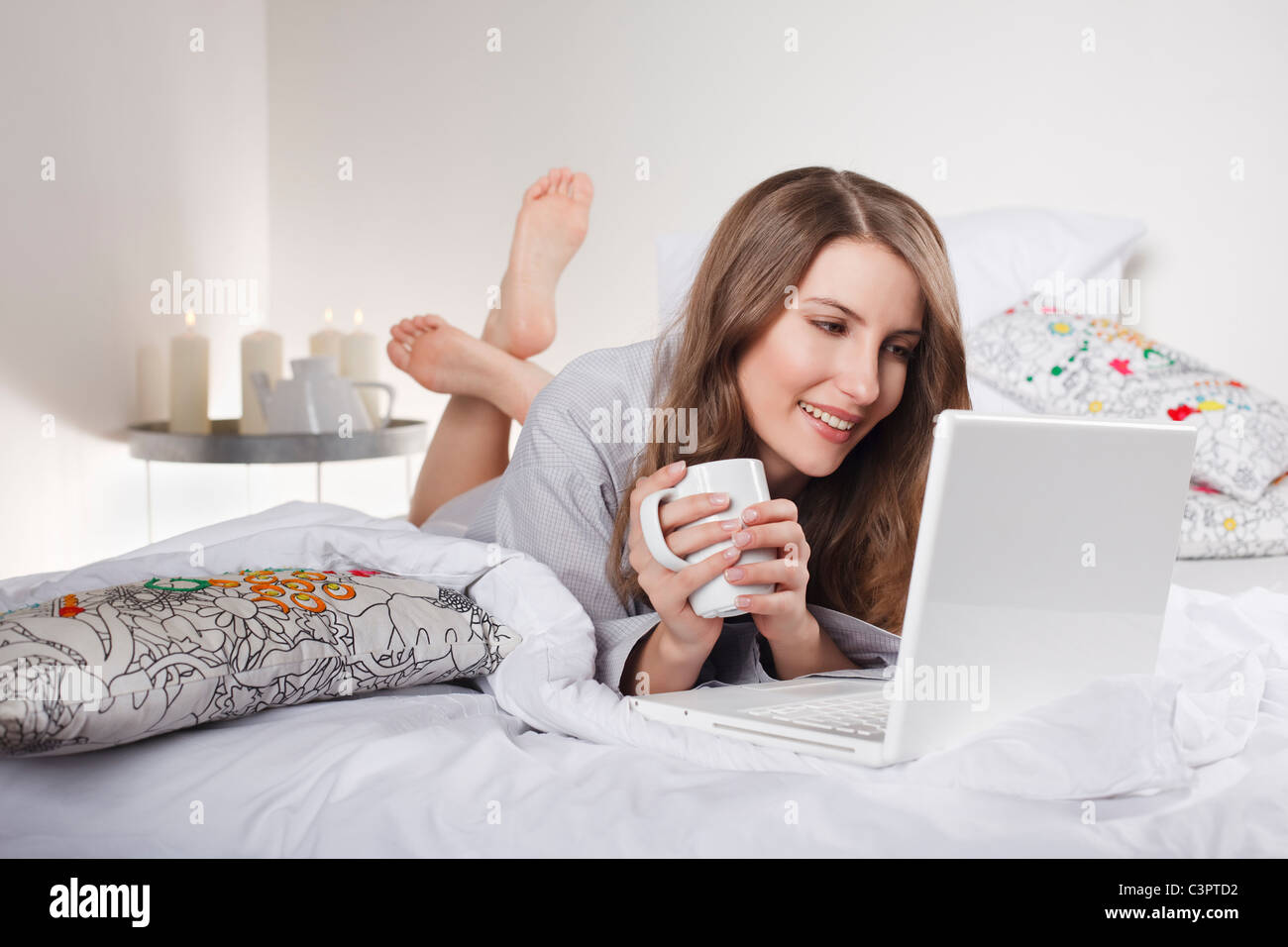 Woman lying on bed with laptop, smiling Stock Photo - Alamy