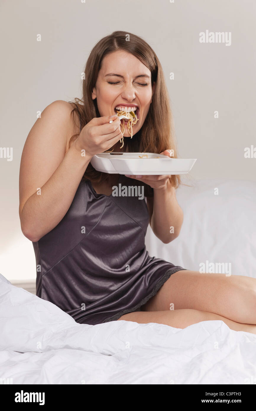 Woman sitting on bed and eating asian food Stock Photo - Alamy