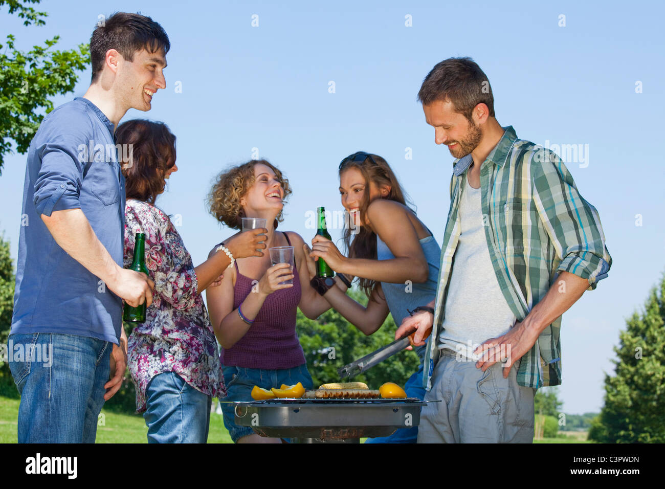 Germany, Munich, Man cooking food and friends smiling Stock Photo - Alamy