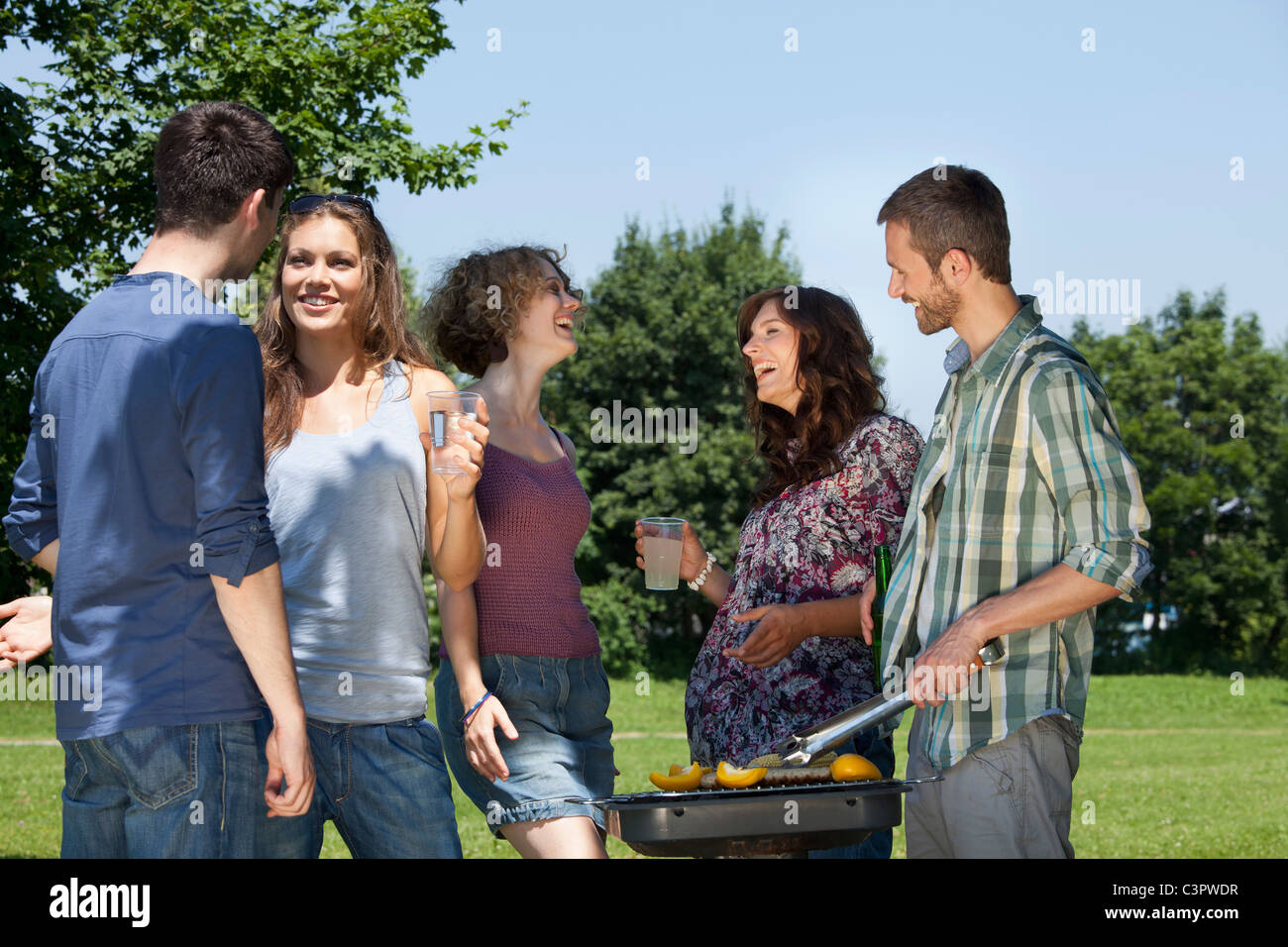 Germany, Munich, Man cooking food and friends smiling Stock Photo - Alamy
