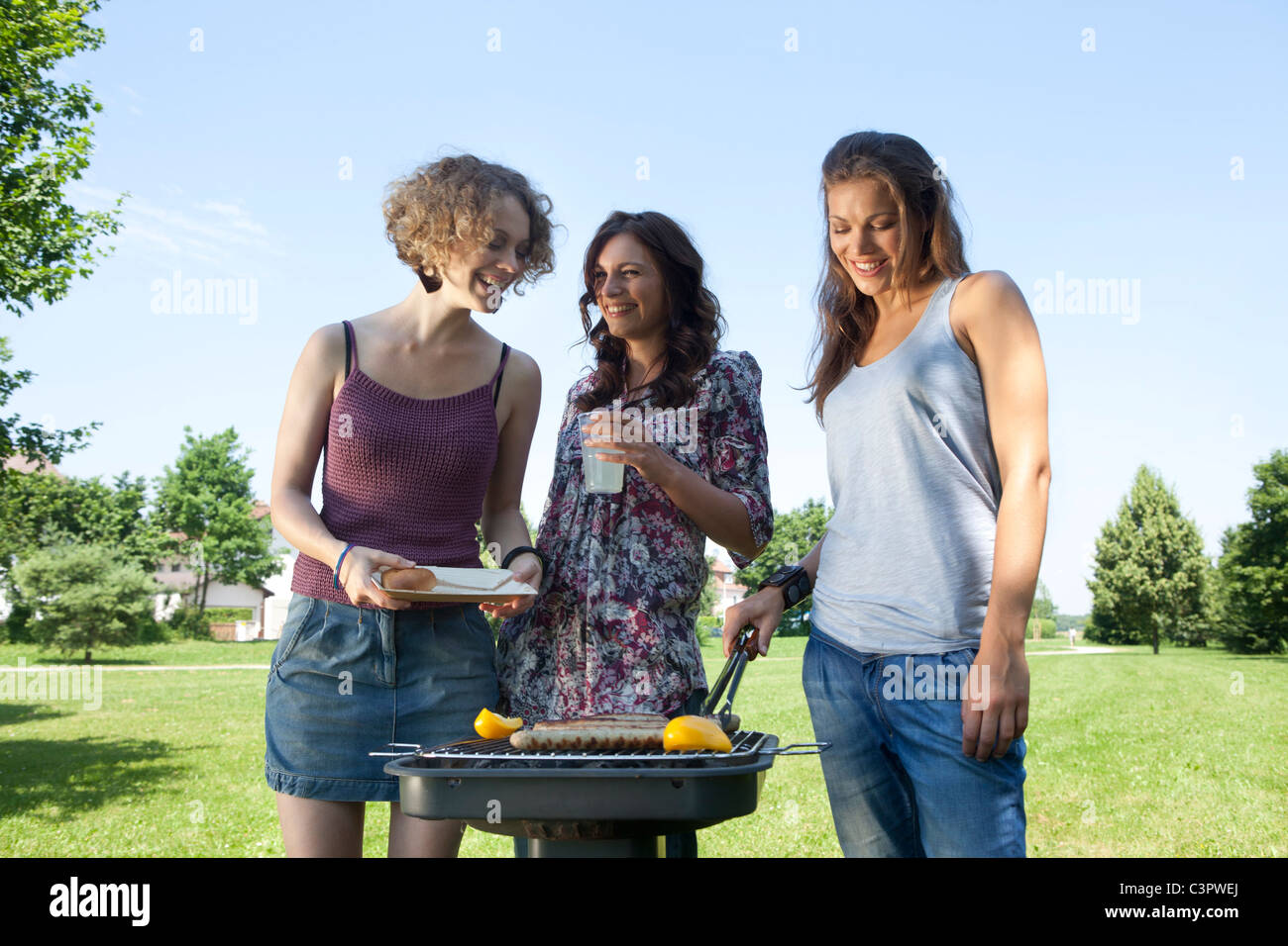 Germany, Munich, Woman cooking and friends smiling Stock Photo - Alamy