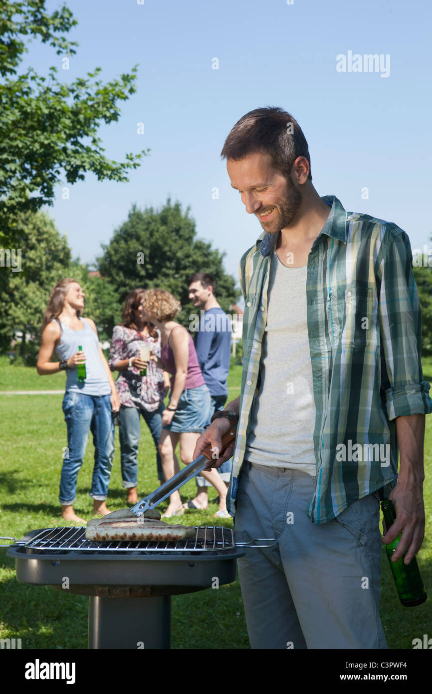 Germany, Munich, Man cooking food and friends enjoying in background ...