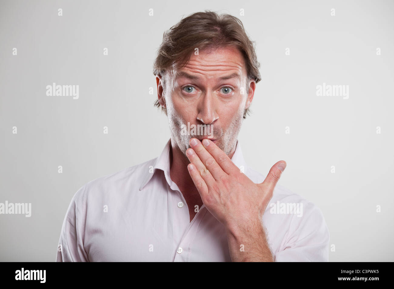 Man with hand over mouth, portrait Stock Photo - Alamy