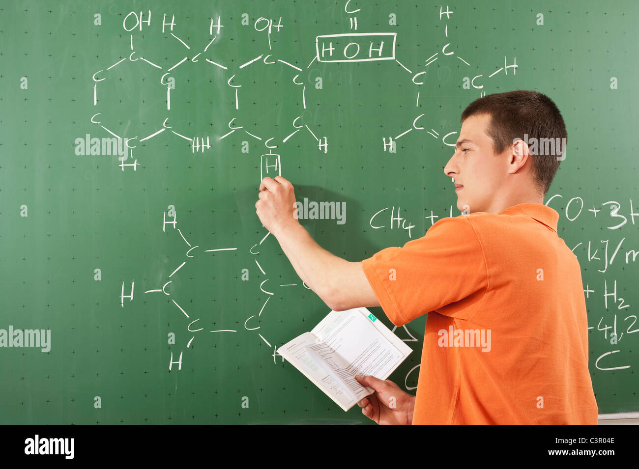 Germany, Emmering, Young man writing formula on board Stock Photo - Alamy