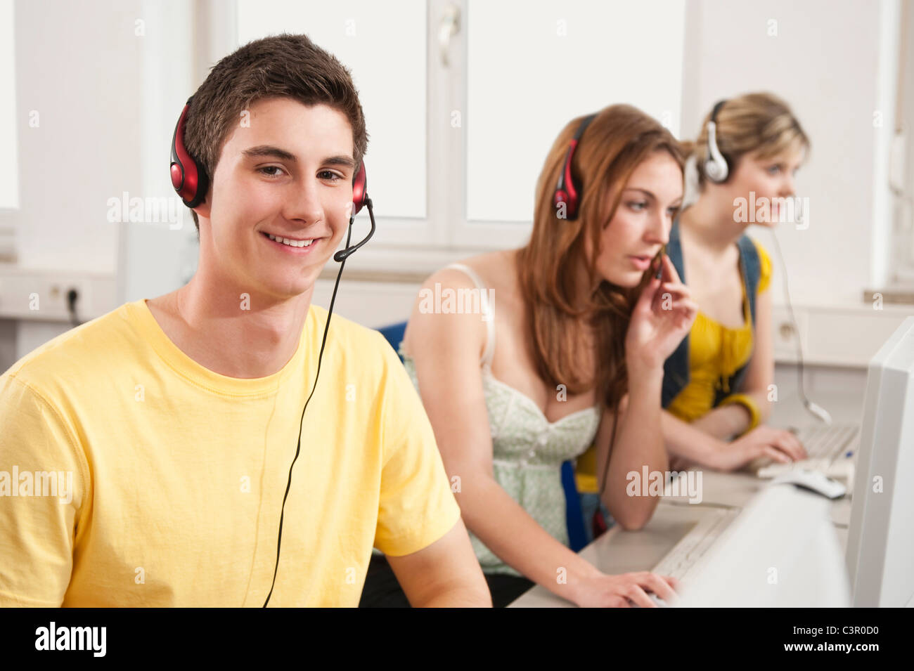 Germany, Emmering, Teenage boy smiling with students using computer in ...
