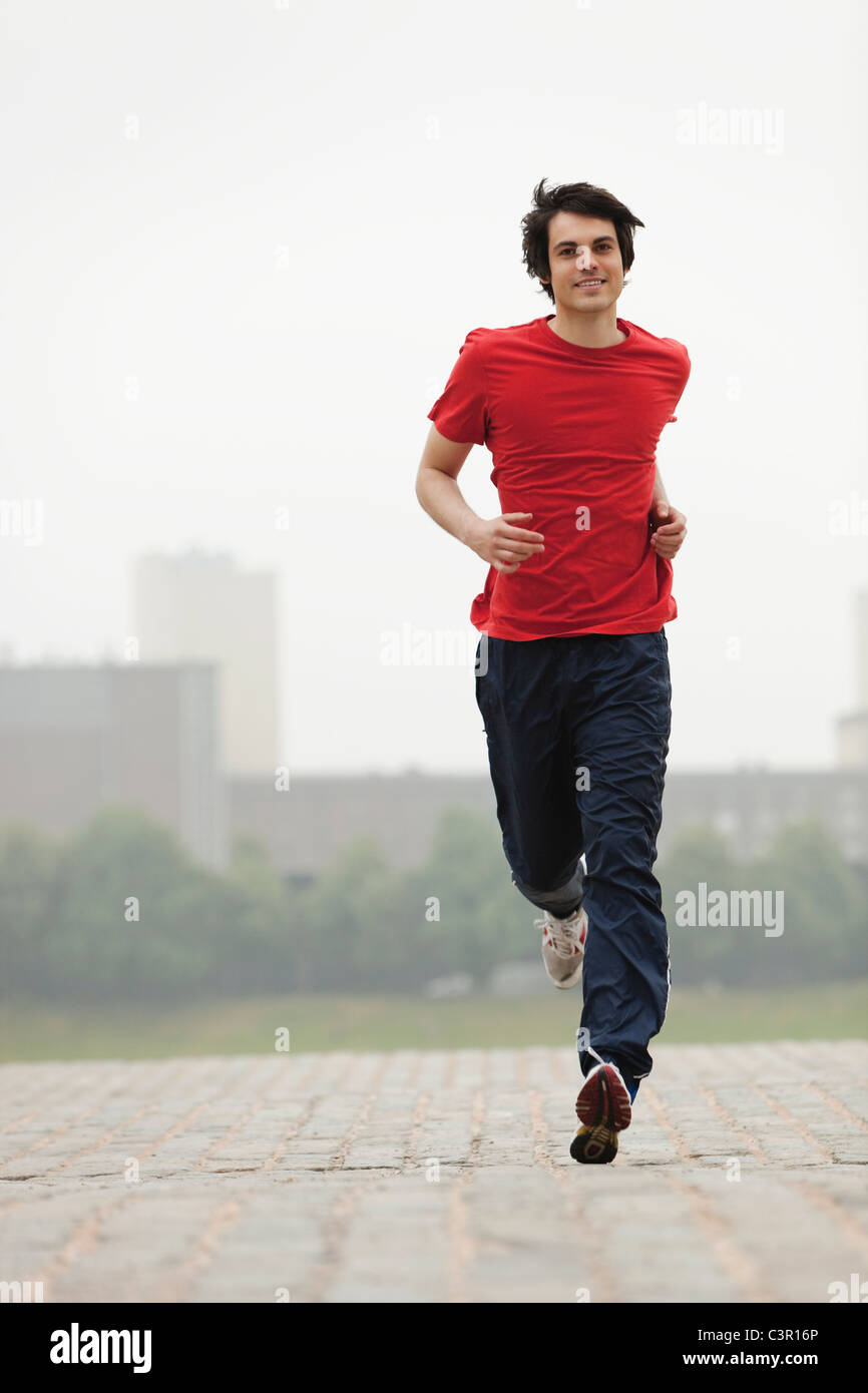 Germany, Cologne, Young man jogging, smiling Stock Photo - Alamy