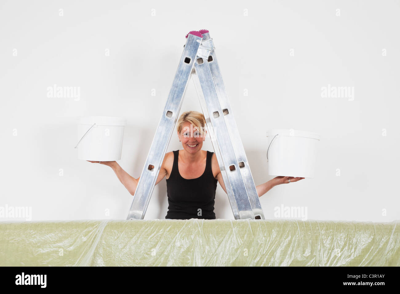 Germany, Cologne, Mature woman using paint buckets for workout ...