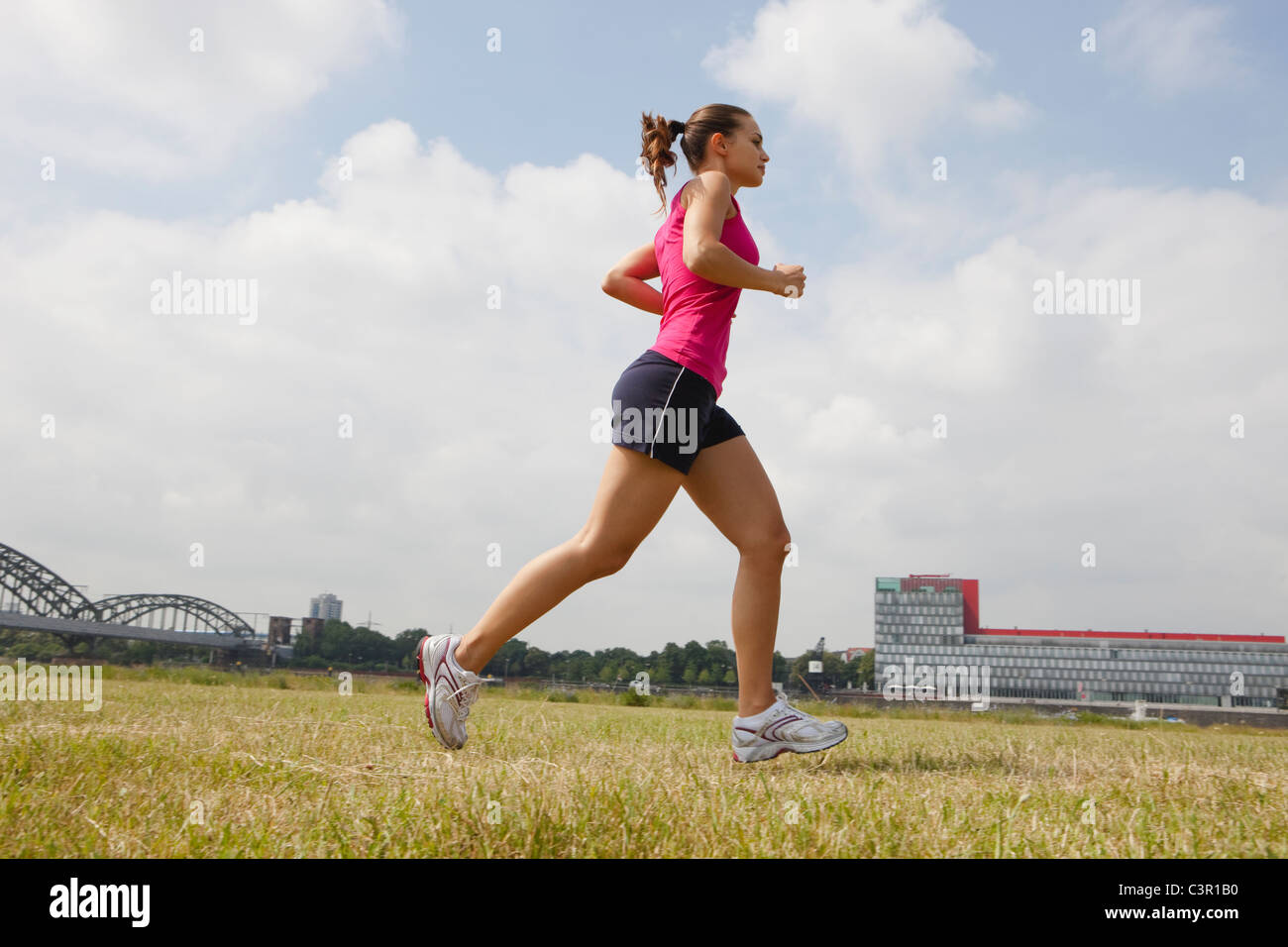 Germany, Cologne, Young woman jogging in field Stock Photo - Alamy