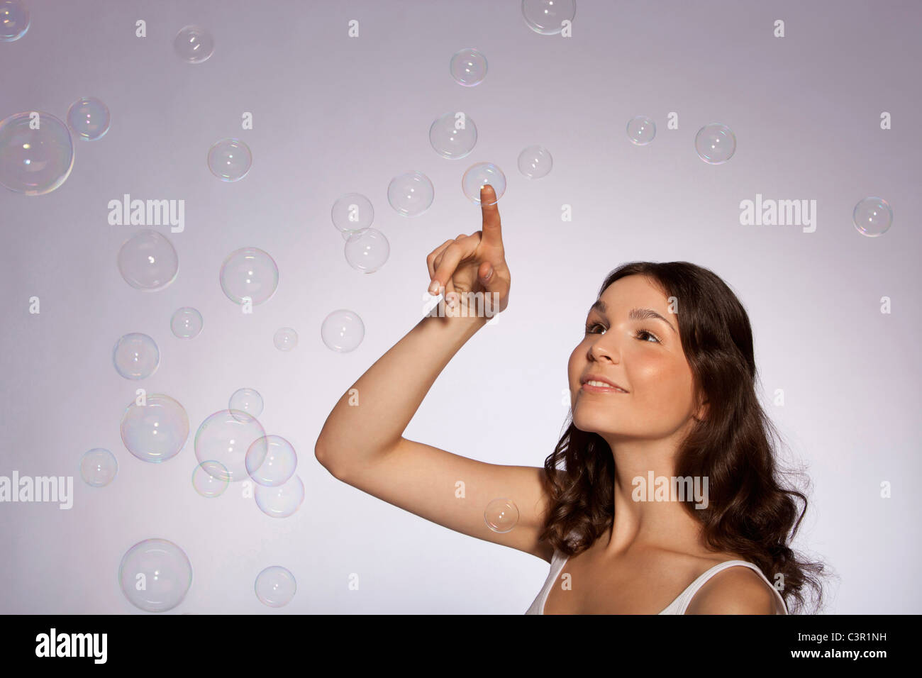 Young woman touching soap bubble, smiling Stock Photo - Alamy