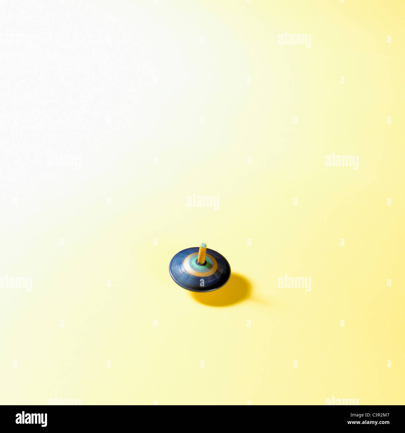 Pegtop spinner spinning on Yellow Background Stock Photo - Alamy