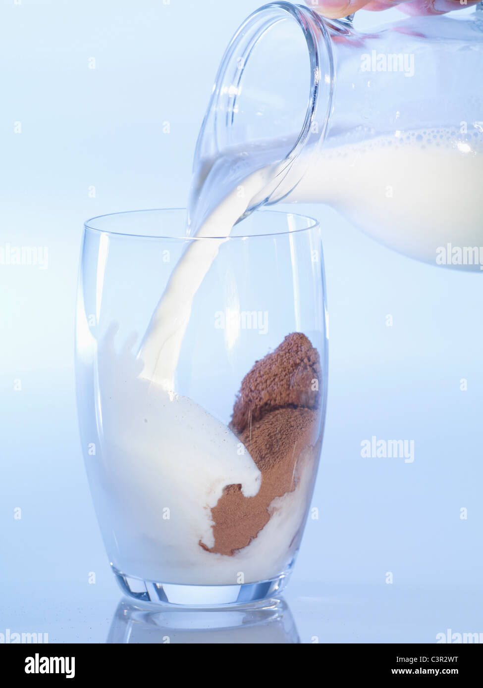 Human hand pouring milk into glass of cocoa, close-up Stock Photo - Alamy