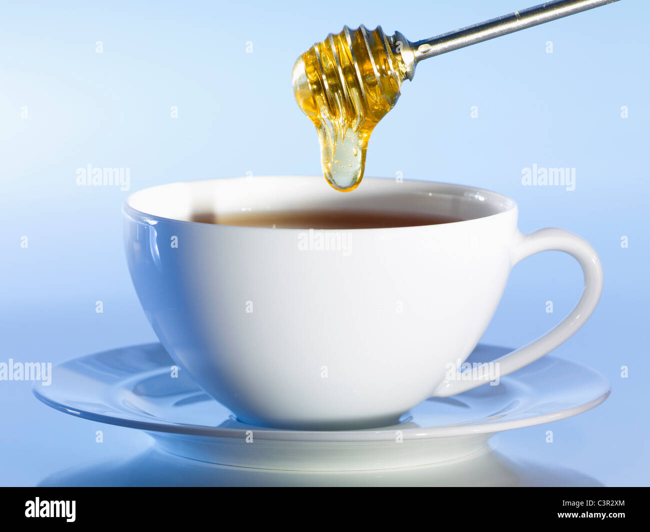 Honey dipper with tea cup, close-up Stock Photo - Alamy